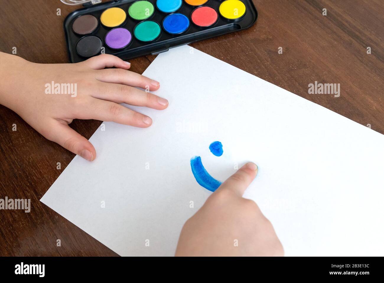 Child girl hand is drawing a Smile face with finger and watercolor ...