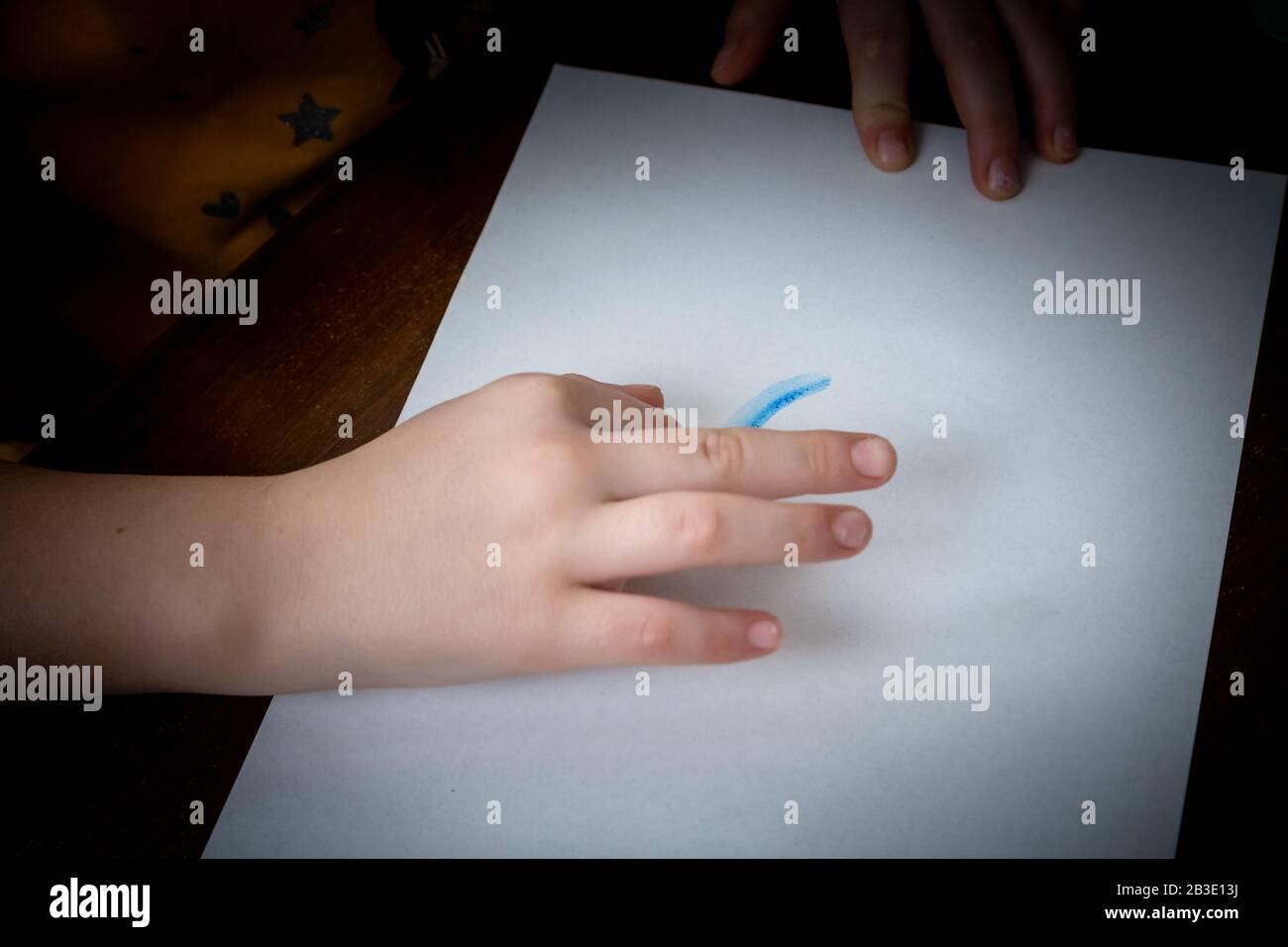 A little child girl hand is drawing by watercolor paints and her finger ...