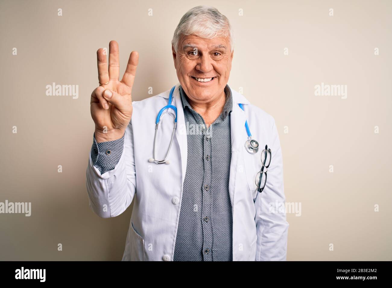 Senior handsome hoary doctor man wearing coat and stethoscope over ...