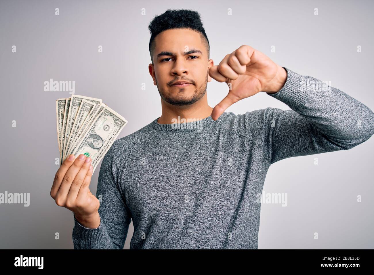 Young handsome man holding bunch of dollars banknotes over isolated ...