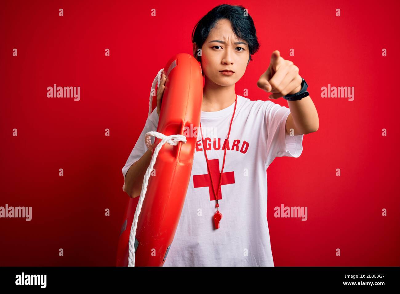 Young beautiful asian lifeguard girl using whistle holding orange float ...