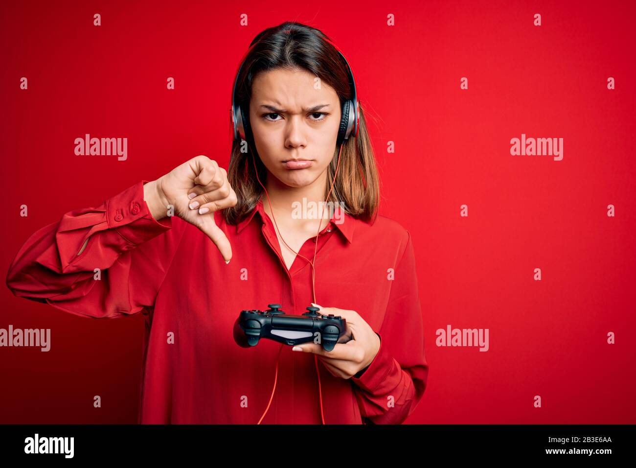 Young beautiful brunette gamer girl playing video game using joystick ...