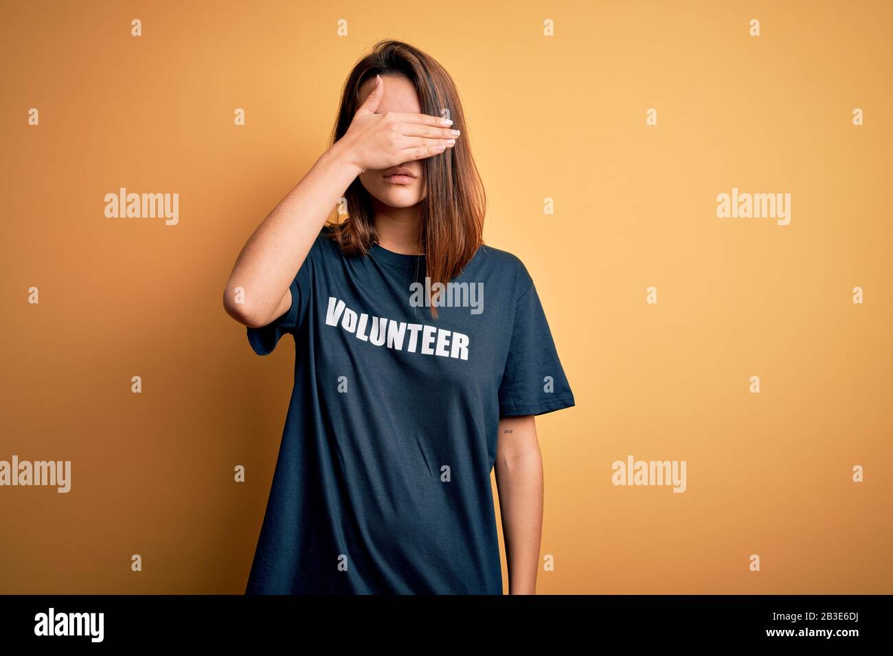 Young beautiful brunette girl doing volunteering wearing t-shirt with ...