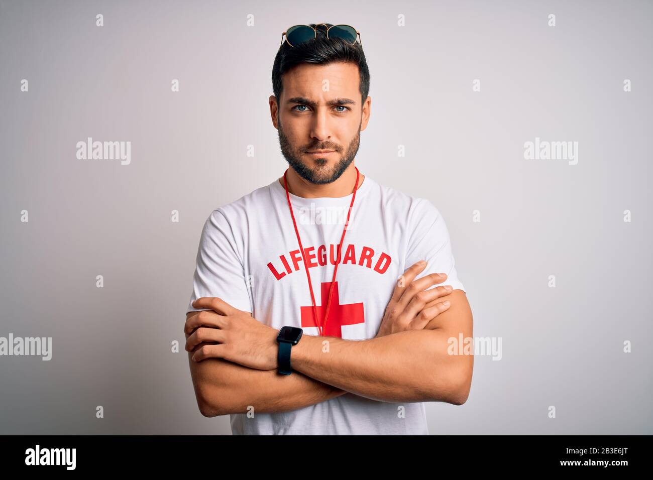 Young handsome lifeguard man with beard wearing t-shirt with red cross ...