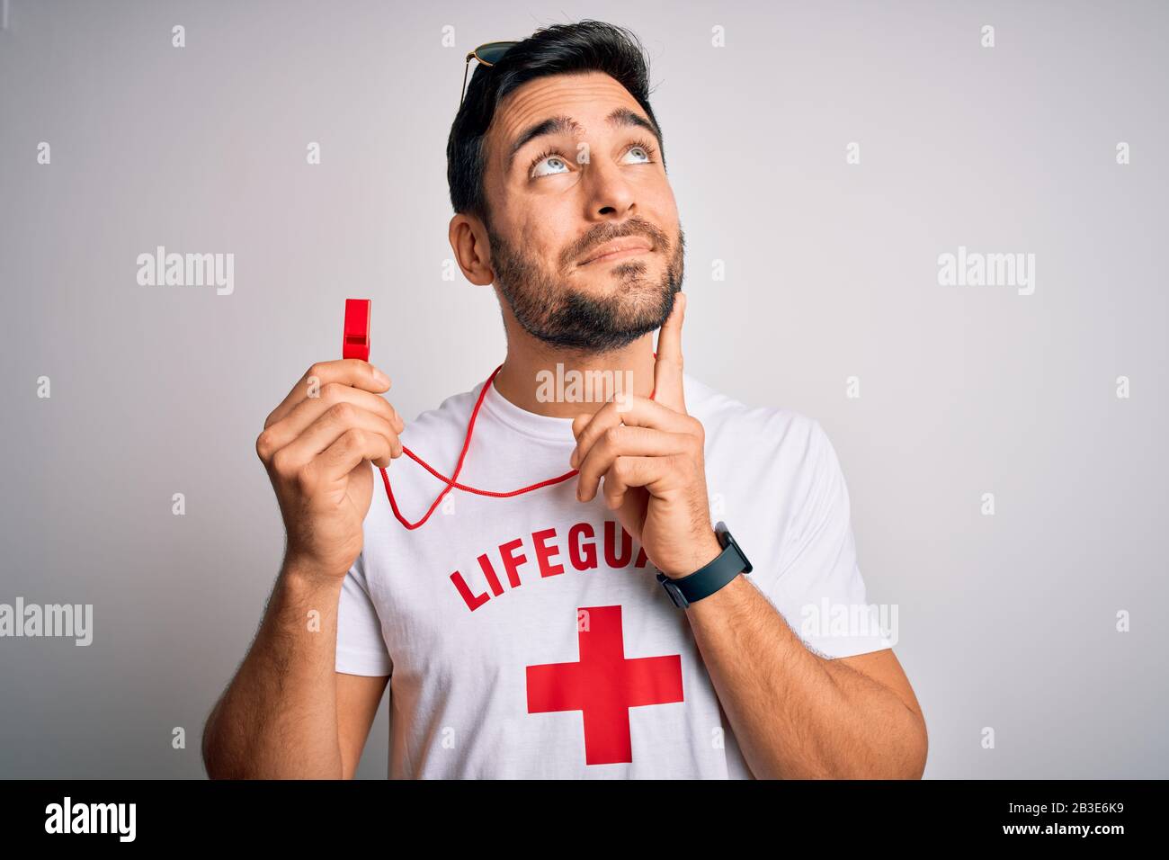 Young lifeguard man with beard wearing t-shirt with red cross and ...