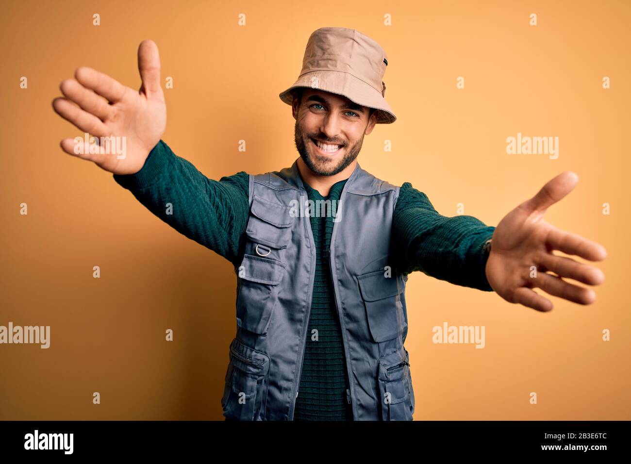 Handsome tourist man with beard on vacation wearing explorer hat over ...