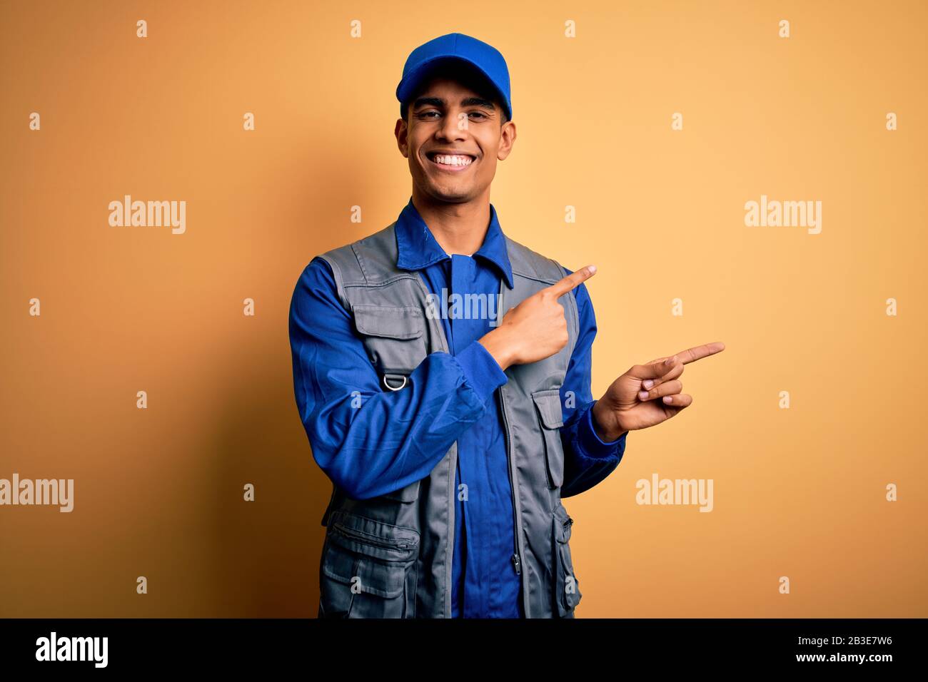 Young handsome african american handyman wearing worker uniform and cap ...