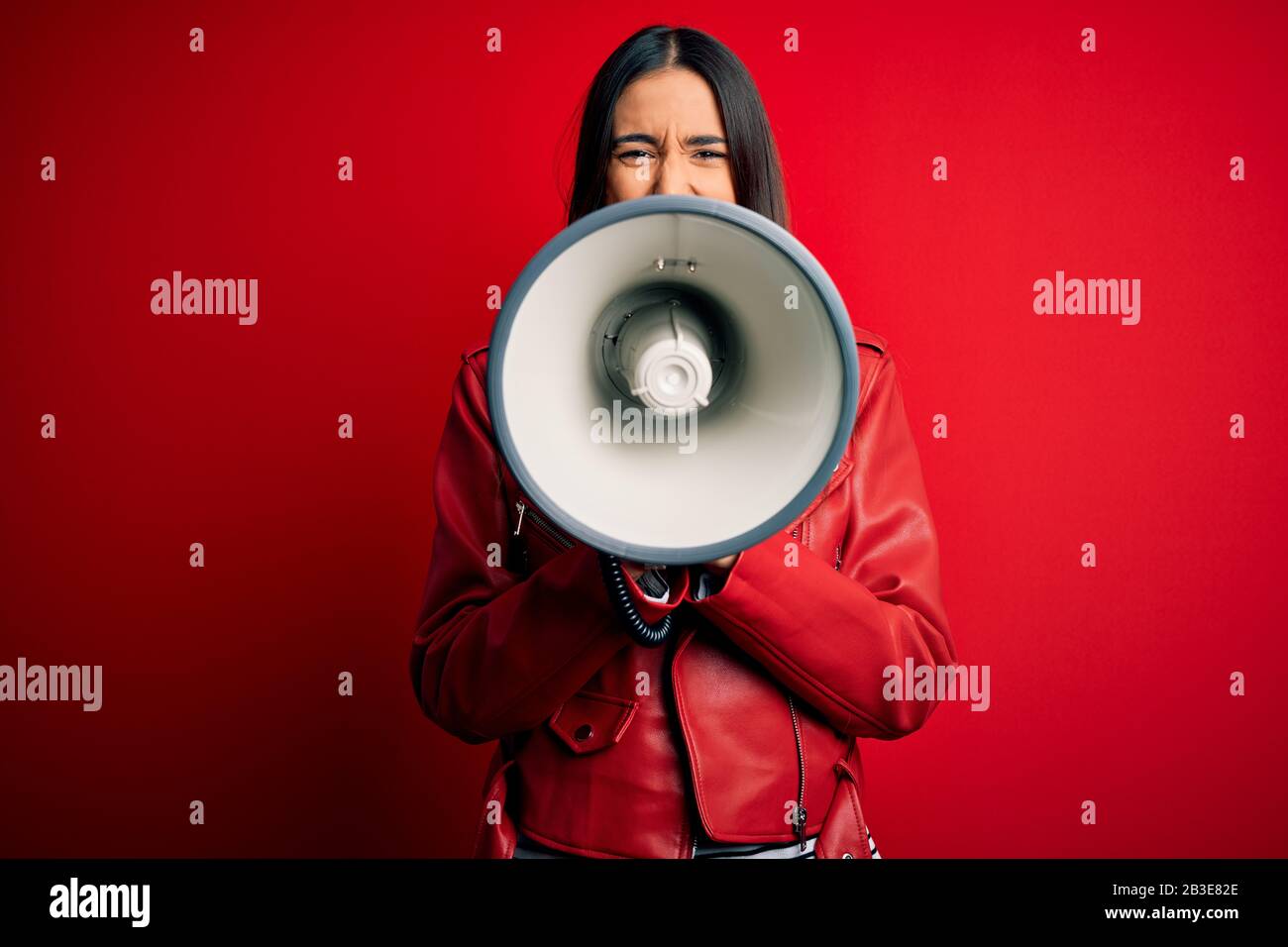 Hispanic woman shouting angry on protest through megaphone. Yelling ...