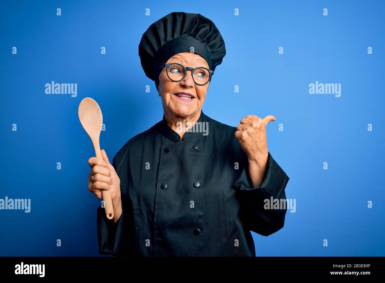 Senior beautiful grey-haired chef woman wearing cooker uniform and hat ...