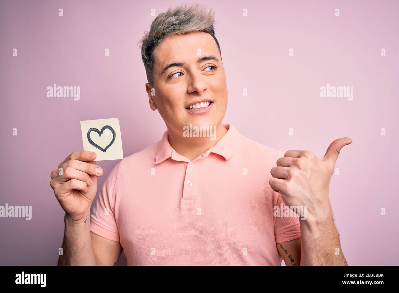 Young modern romantic man holding heart shape drawing over isolated ...