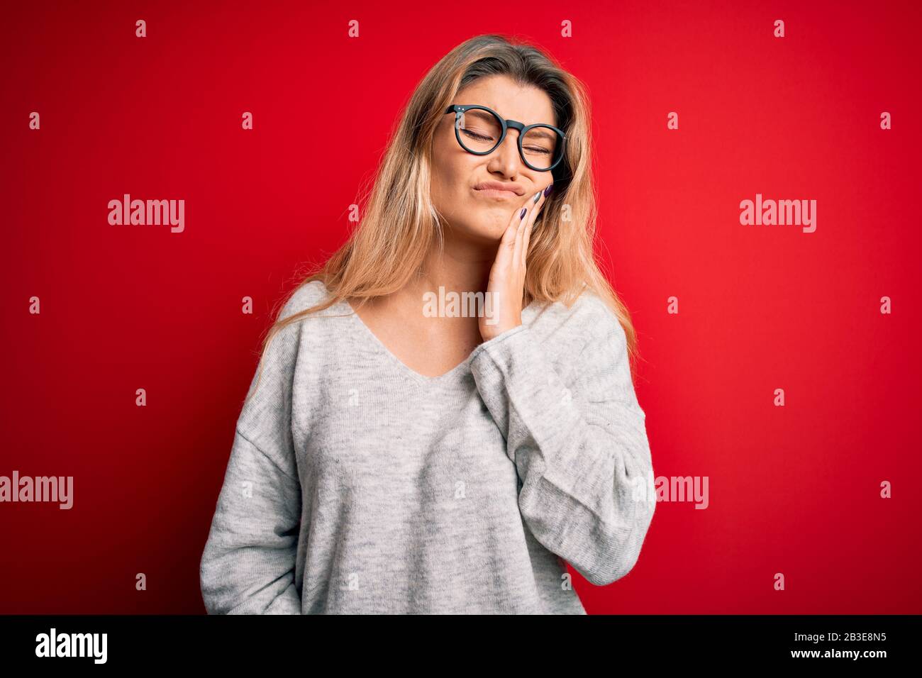 Young beautiful blonde woman wearing sweater and glasses over isolated ...
