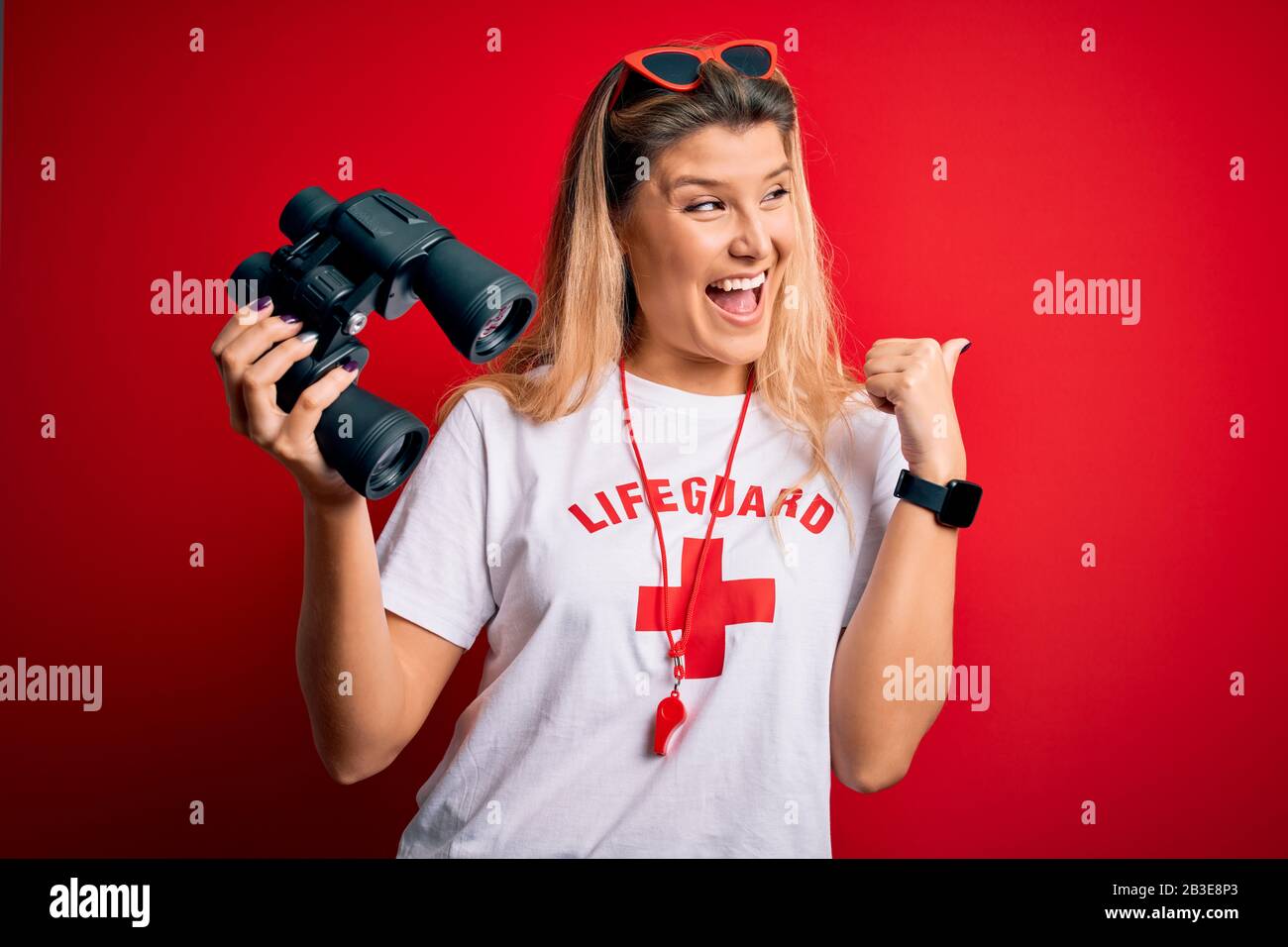 Young beautiful blonde lifeguard woman using binoculars and whistle ...