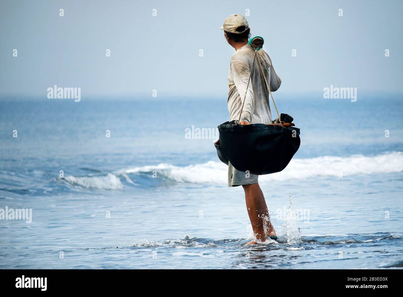 Farmer collecting water in the sea, to salt field for evaporation ...