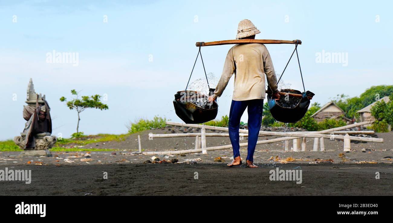 Farmer collecting water in the sea, to salt field for evaporation ...