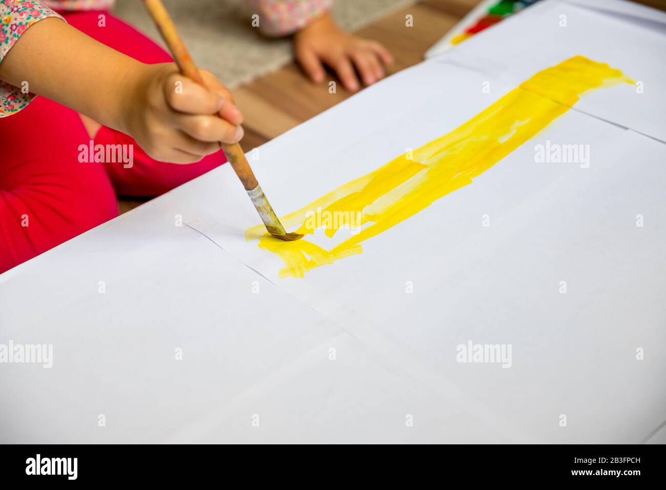 Hands of a kid drawing with highlighters on paper with painting brush ...