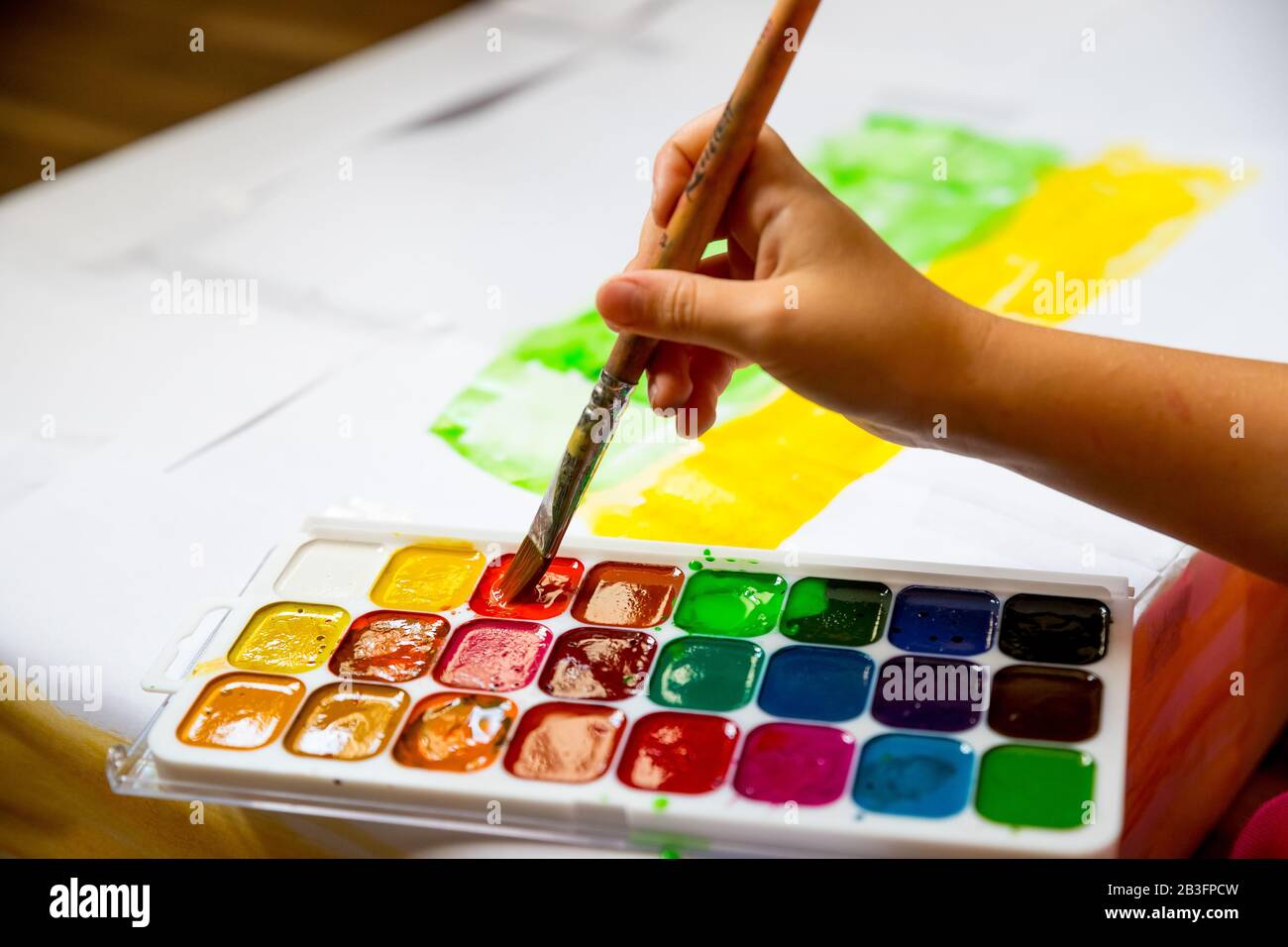 Hands of a kid drawing with highlighters on paper with painting brush ...