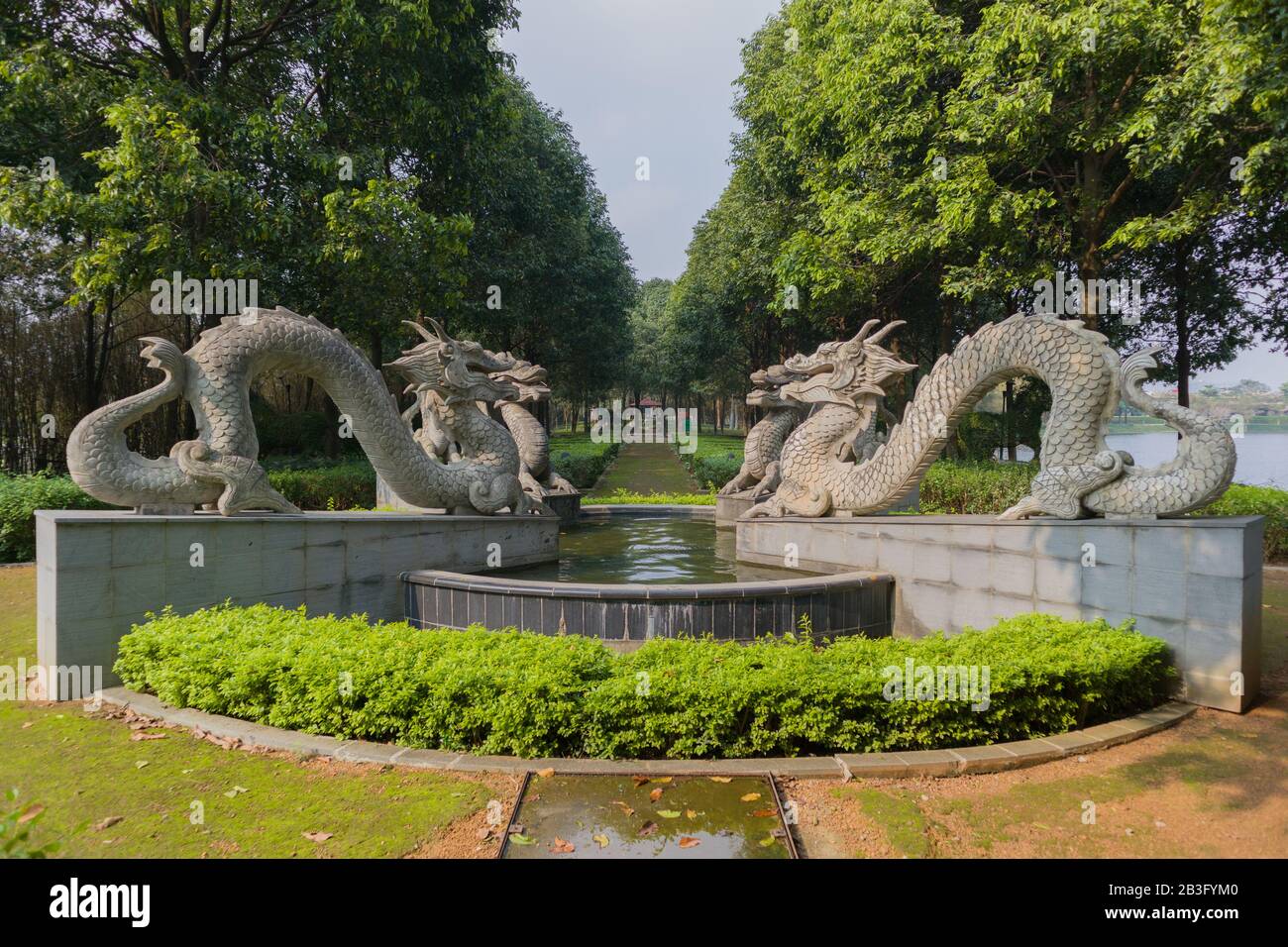 Four dragon statues in a public park with big fountain and green alley ...
