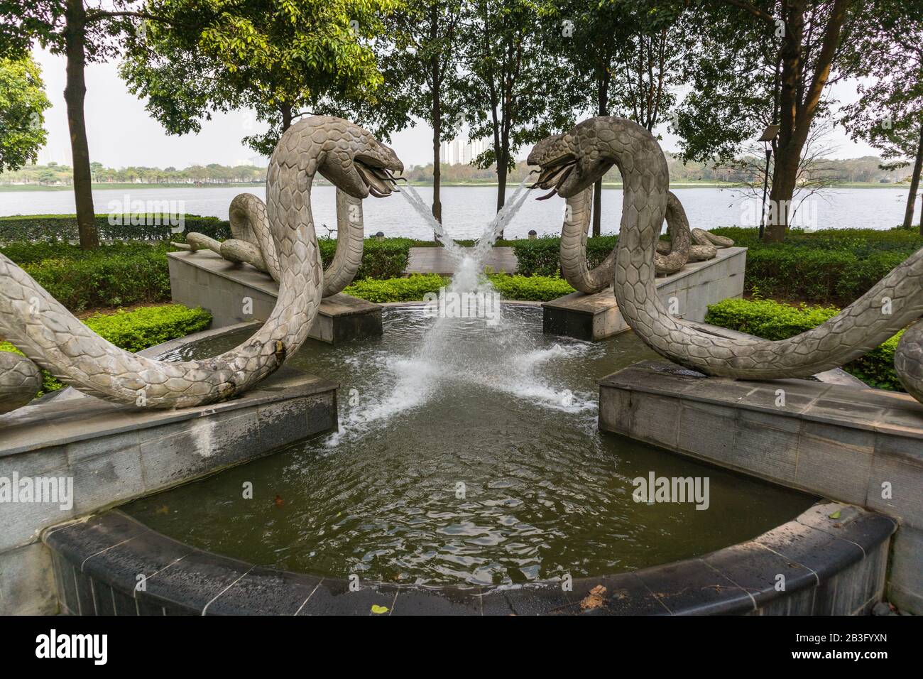 Four snake statues on an active fountain in a public green park Stock ...