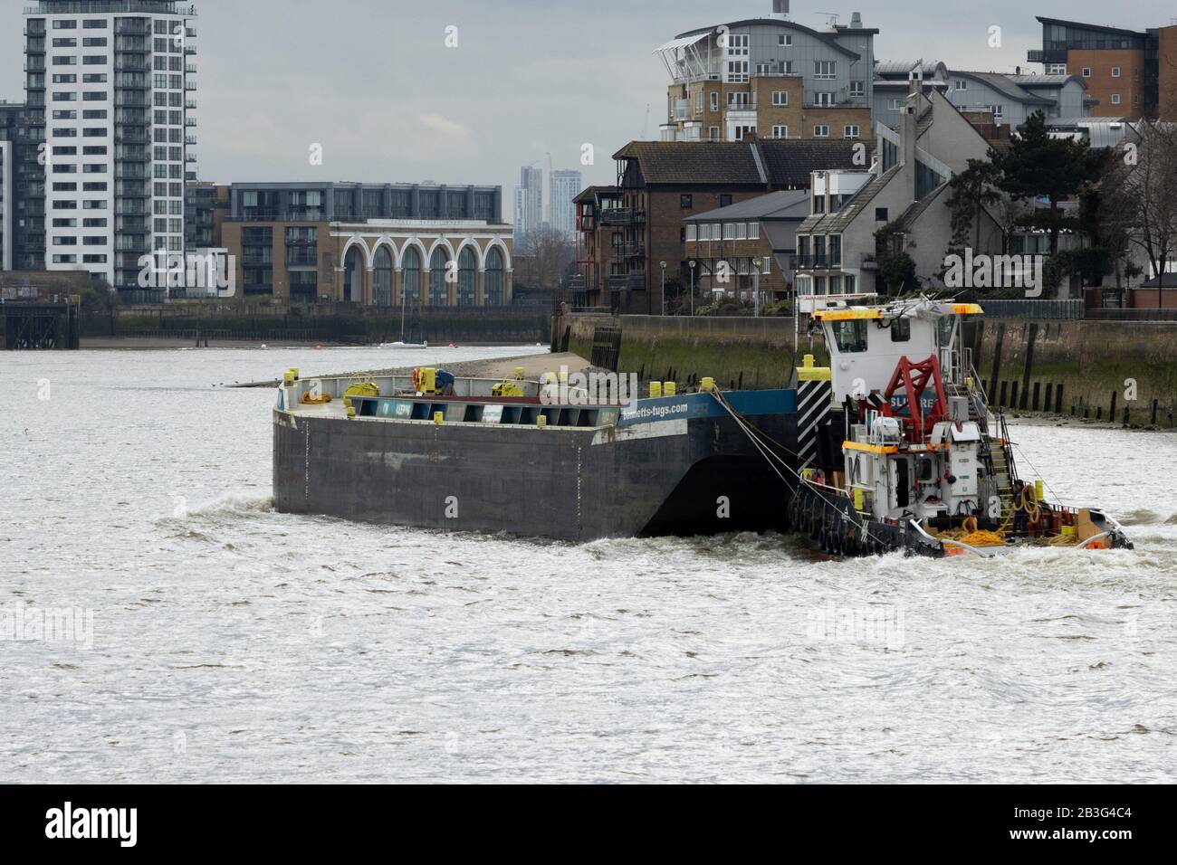 Tug steering load up the Thames Stock Photo - Alamy