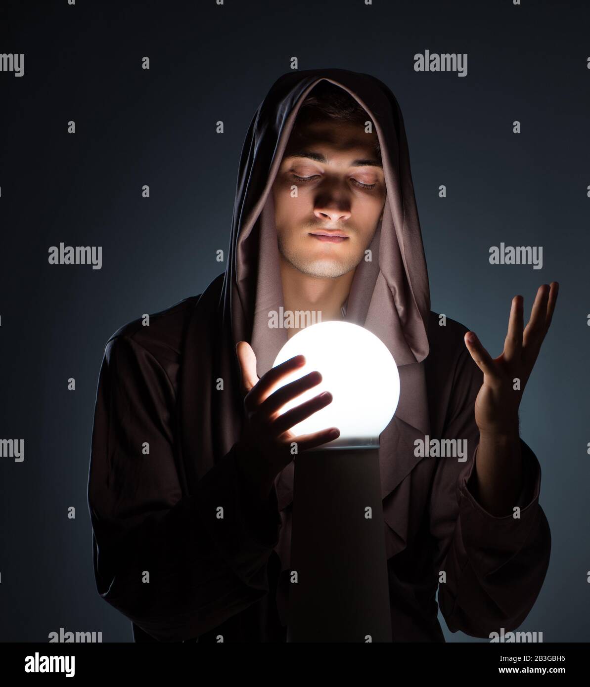 The young wizard with crystal ball in dark room Stock Photo - Alamy
