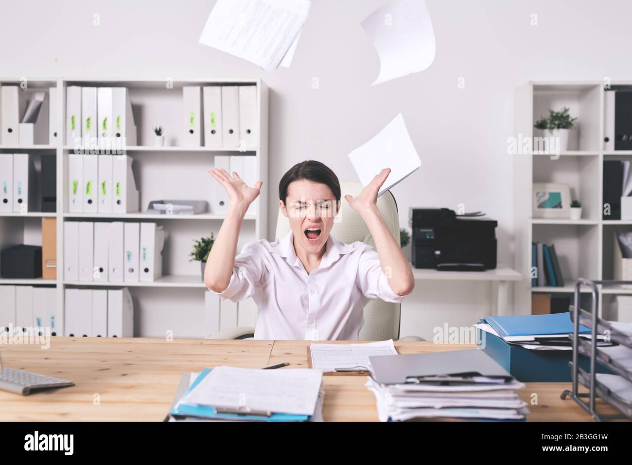 Frustrated young female manager annoyed with paperwork throwing papers ...