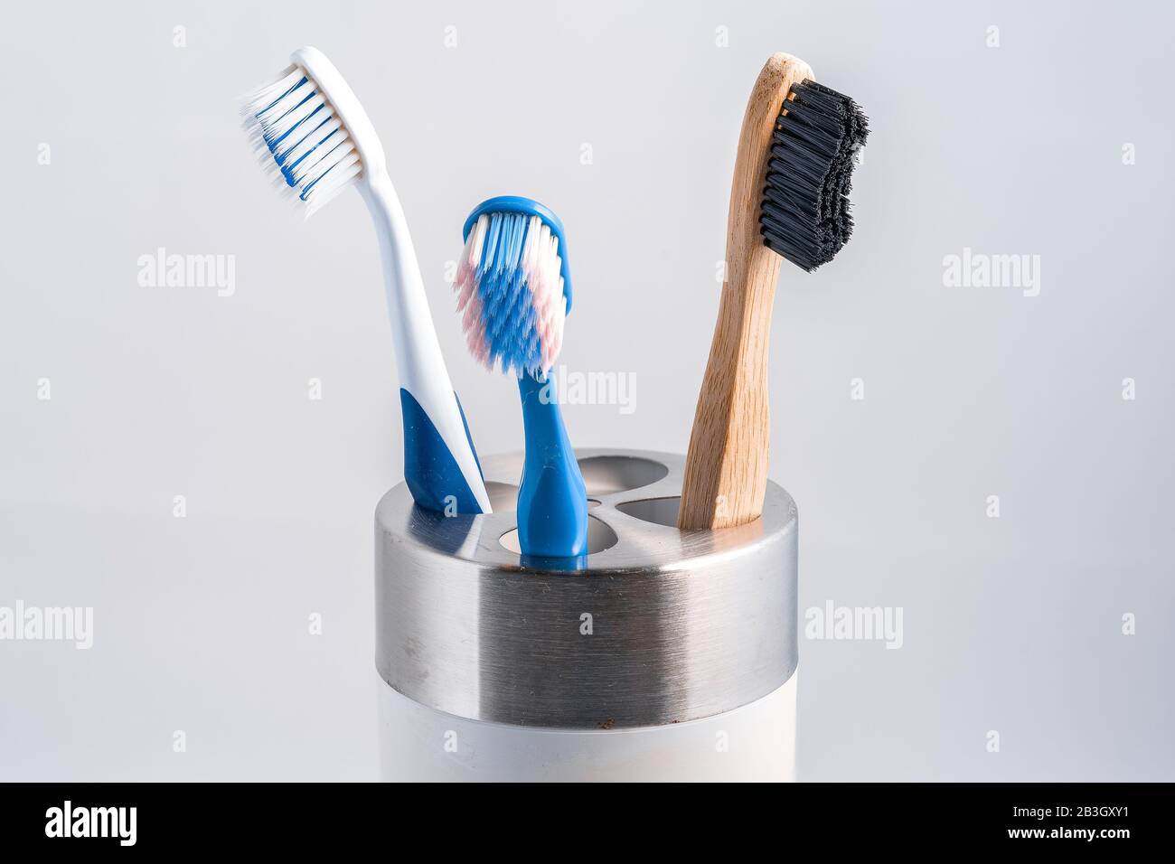 Three toothbrushes in a cup Stock Photo - Alamy
