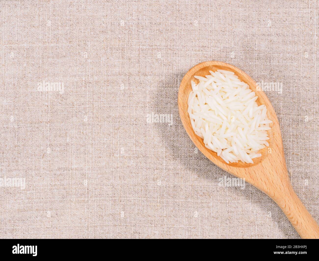 Indian long grain Basmati rice in wooden spoon diagonally on beige ...