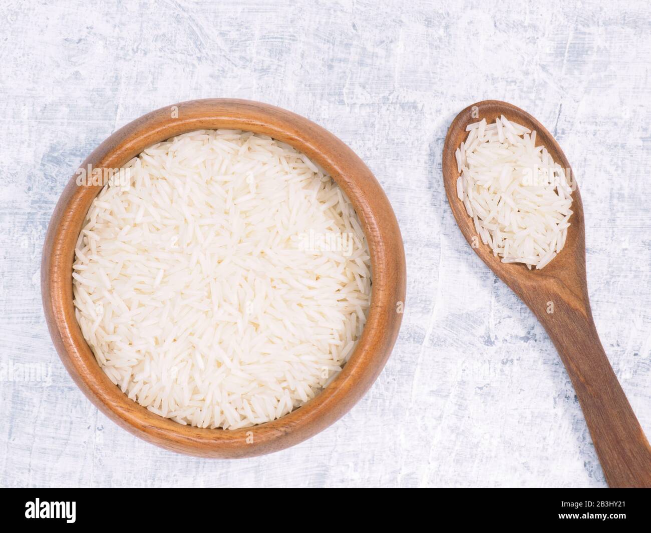 Indian long grain Basmati rice in brown wooden bowl and spoon on white ...