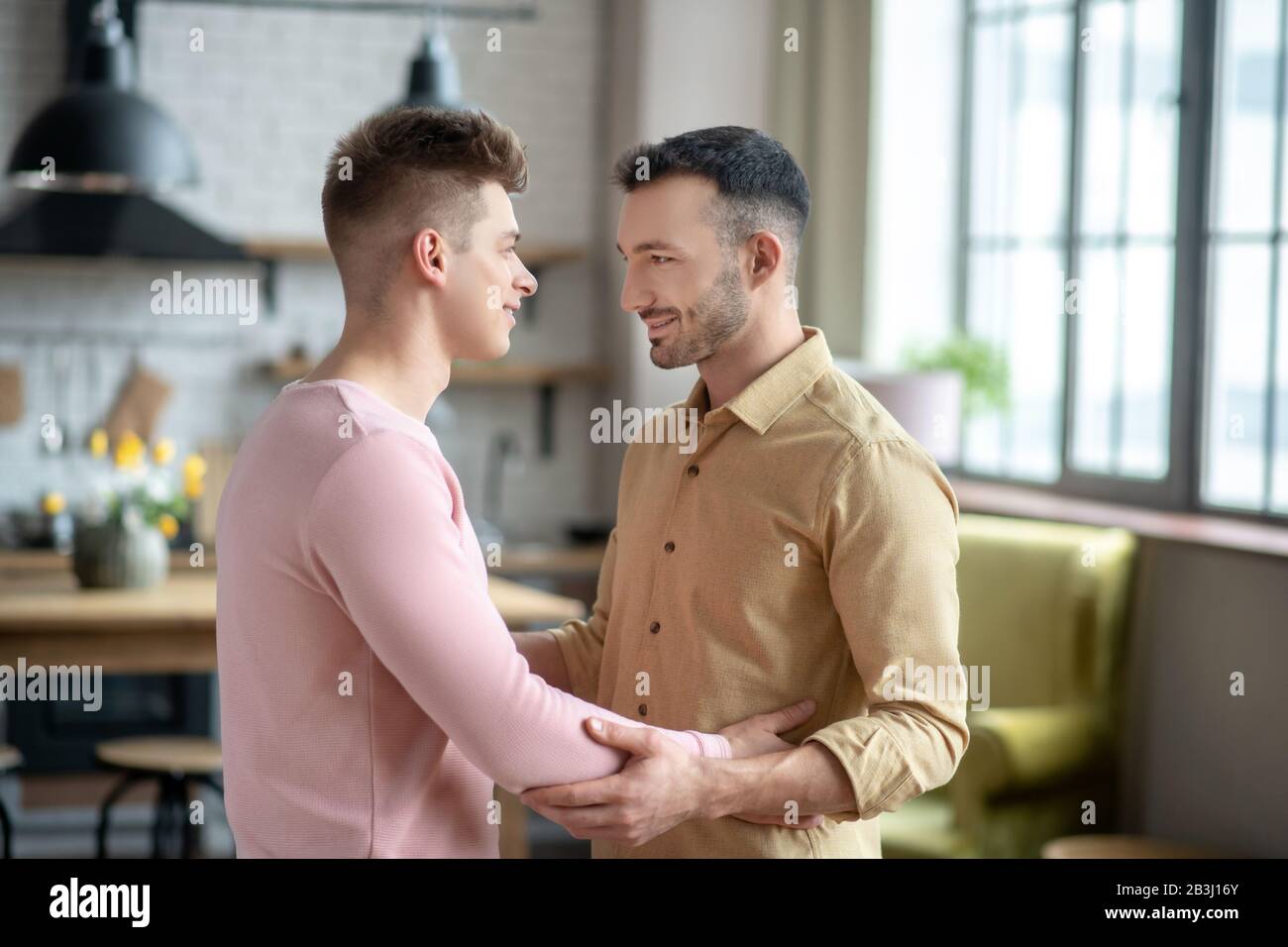 Two young men holding arms and looking at each other Stock Photo - Alamy
