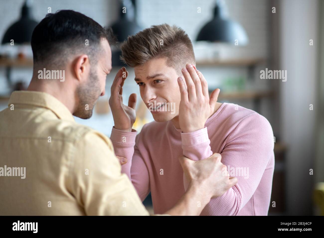 Dark-haired bearded man holding his partners arms looking angry Stock ...