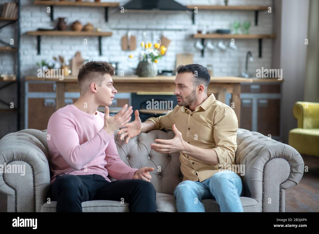 Two men sitting on the sofa having an argument Stock Photo - Alamy