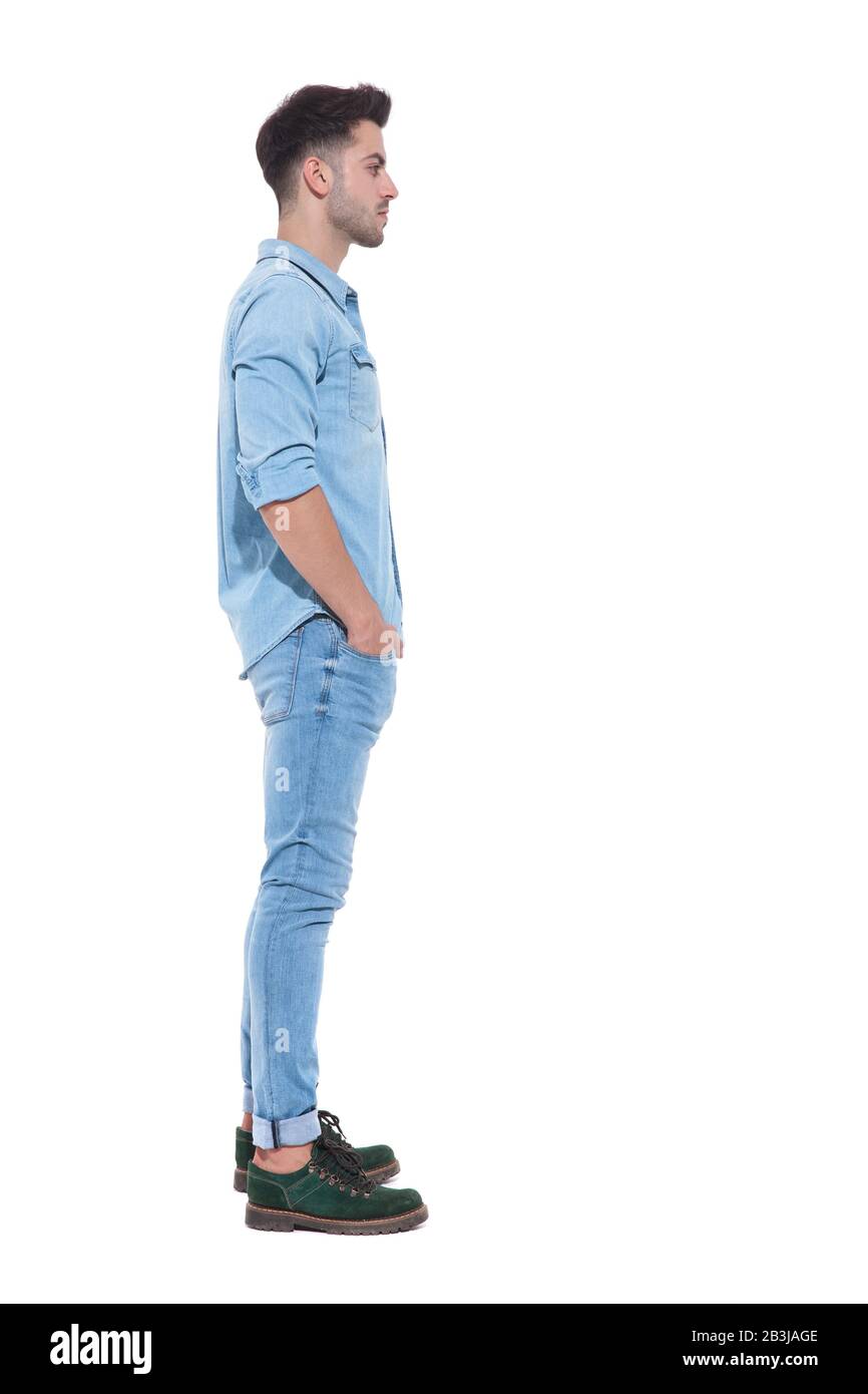 side view of attractive man holding hands in his pockets wearing denim ...