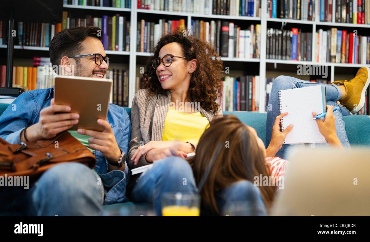 Group of happy students reading books and preparing to exam in library ...