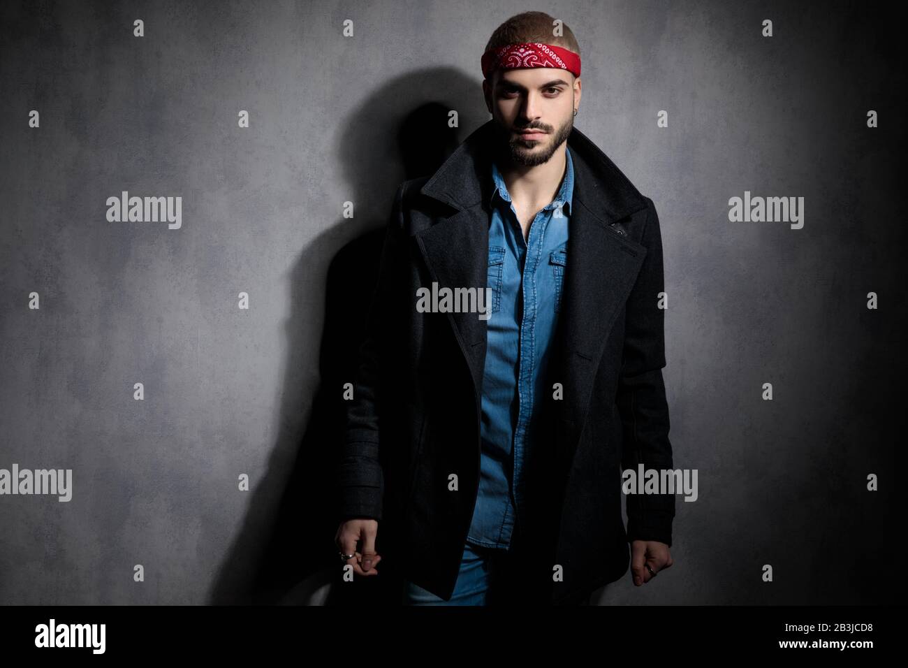 attractive young man wearing a red bandana and a longcoat, standing on ...