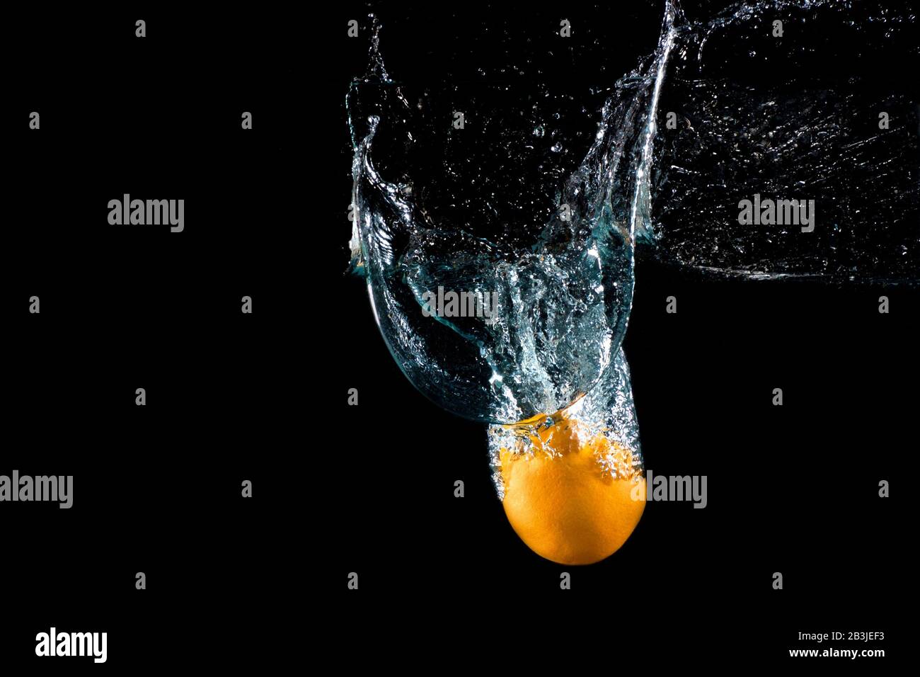 Fresh orange falling in water with splash isolated on black background ...