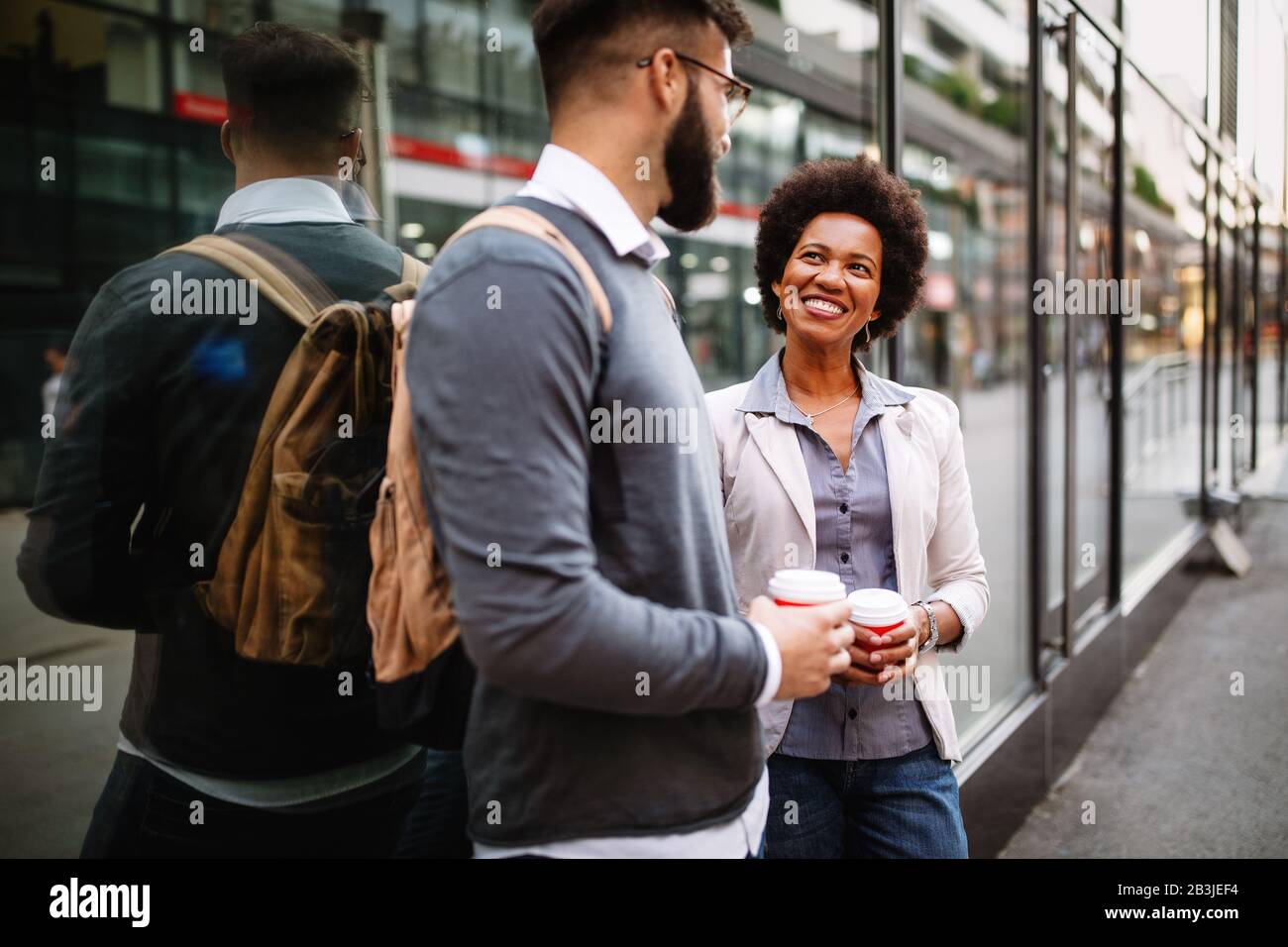Business people discussing and smiling while walking together outdoor ...