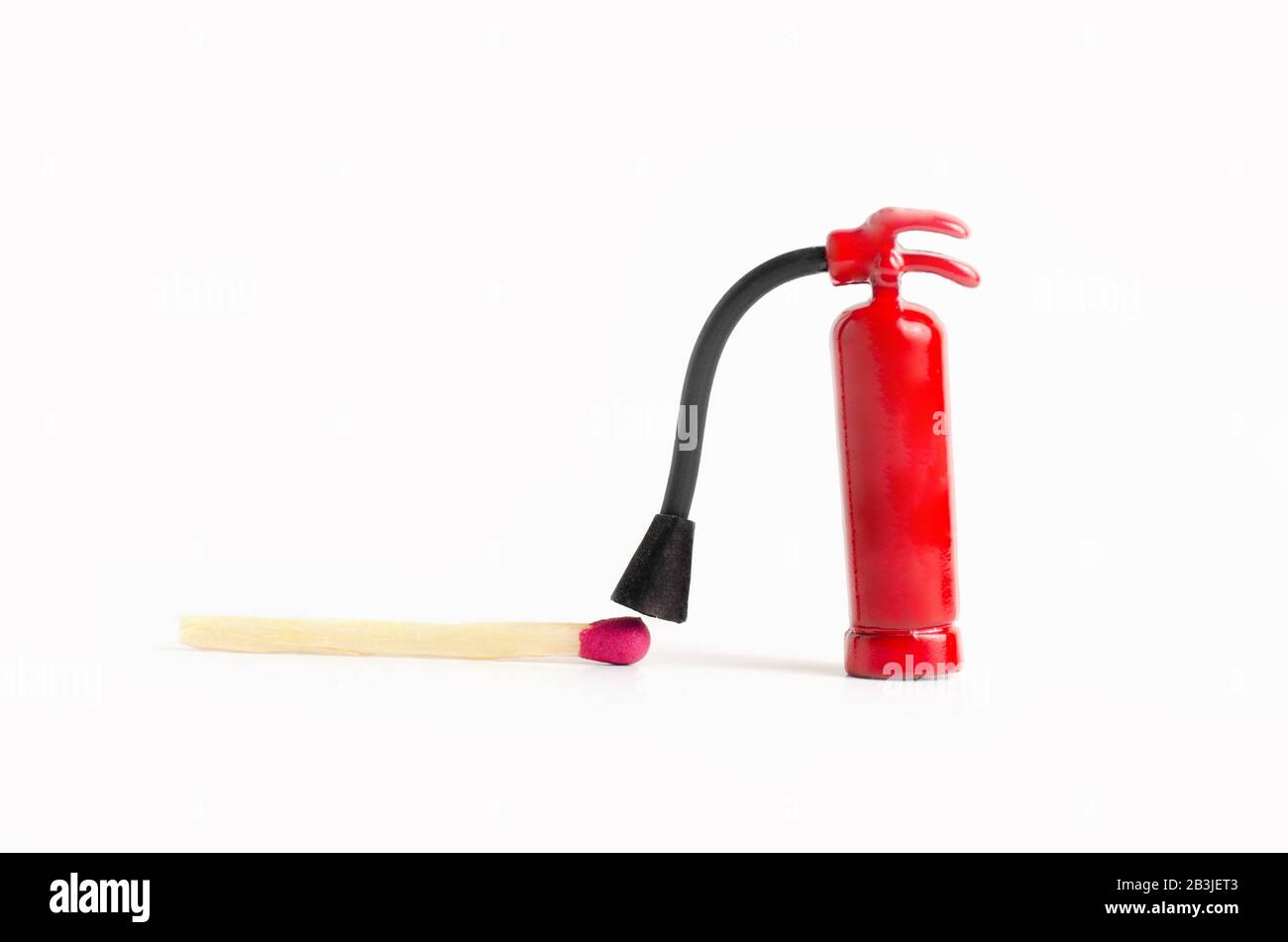 Very small fire extinguisher close to a fresh unburned match against a ...