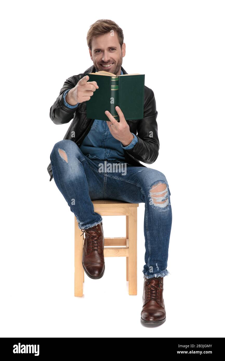 seated casual man reading a book and pointing finger to the camera on ...