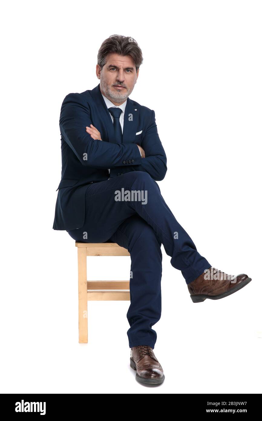 attractive formal business man with navy suit sitting with arms and ...