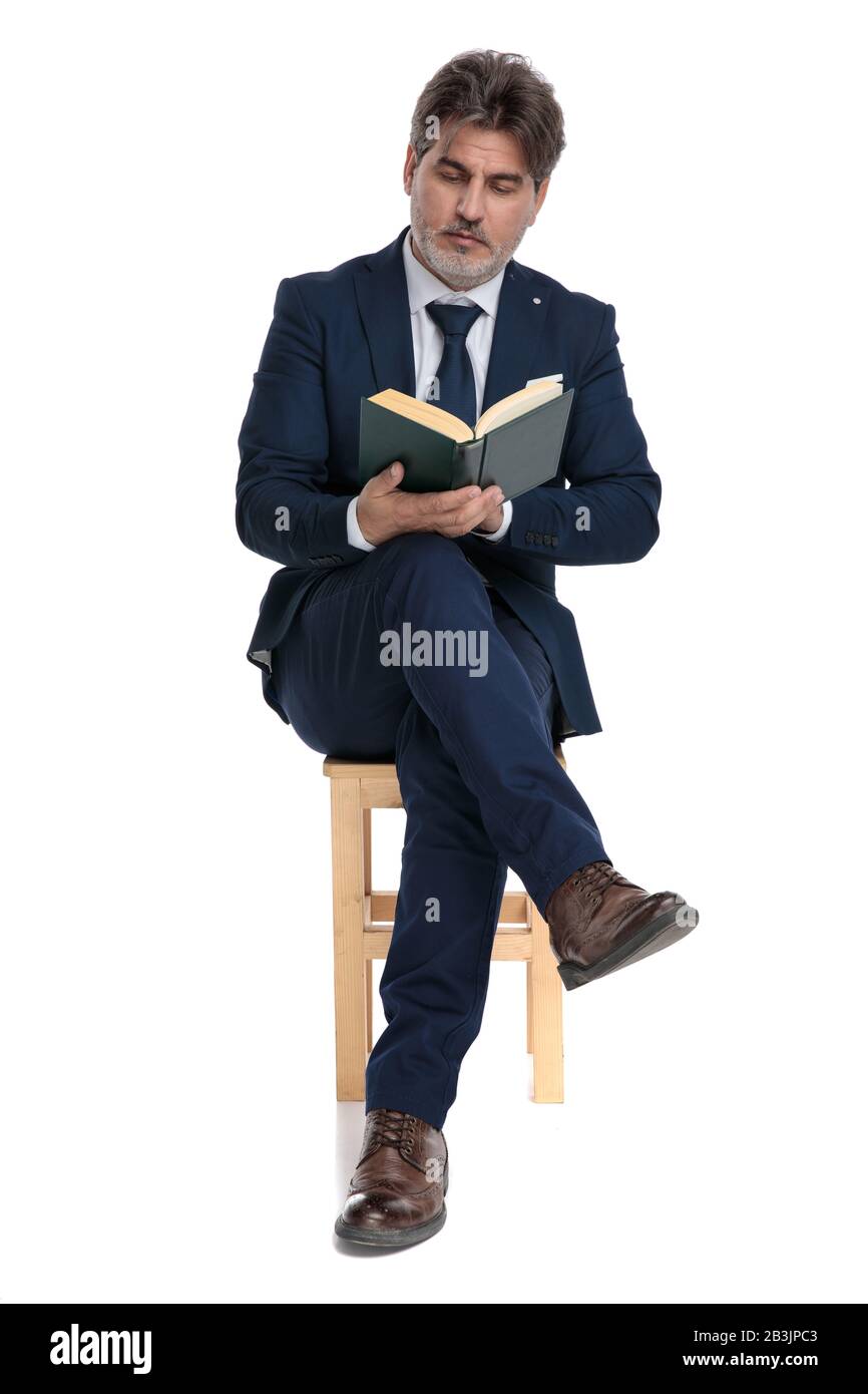 beautiful formal business man with navy suit is sitting with legs ...