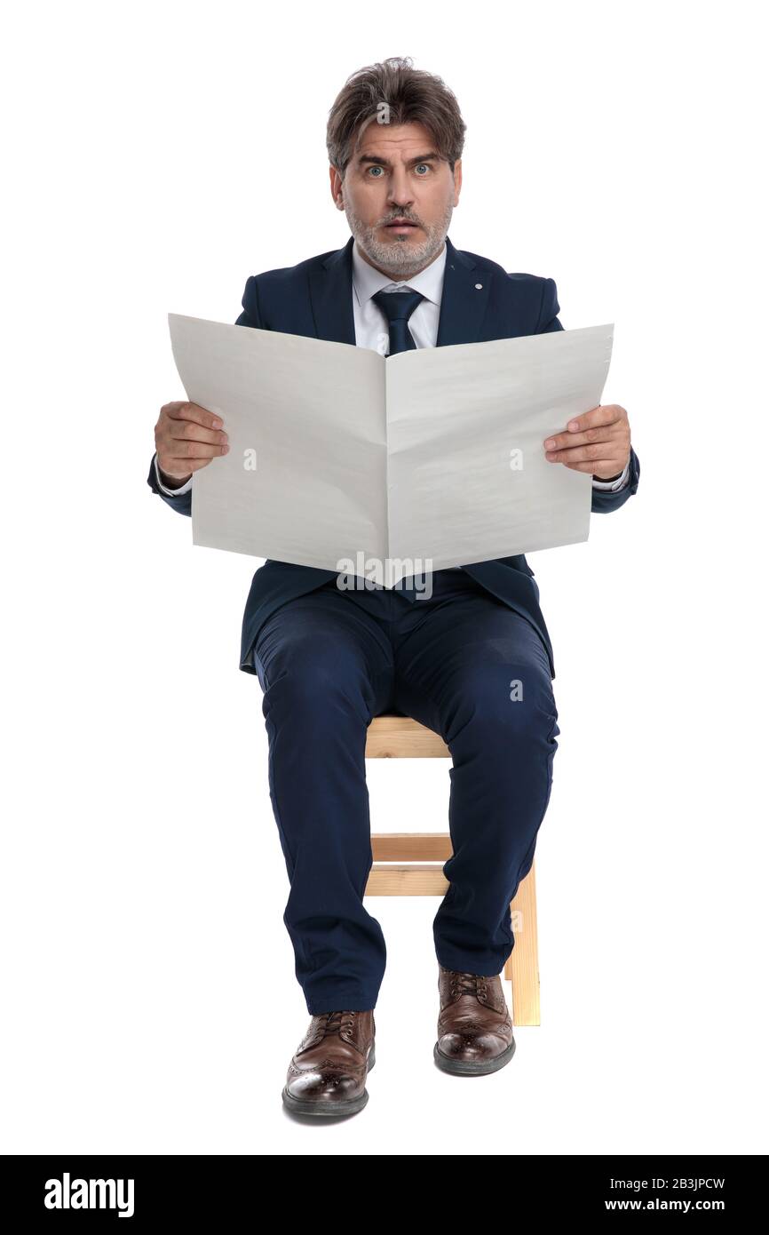 good looking formal business man with navy suit is sitting and holding ...