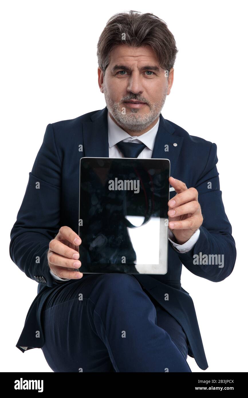 good looking formal business man with navy suit is sitting with crossed ...
