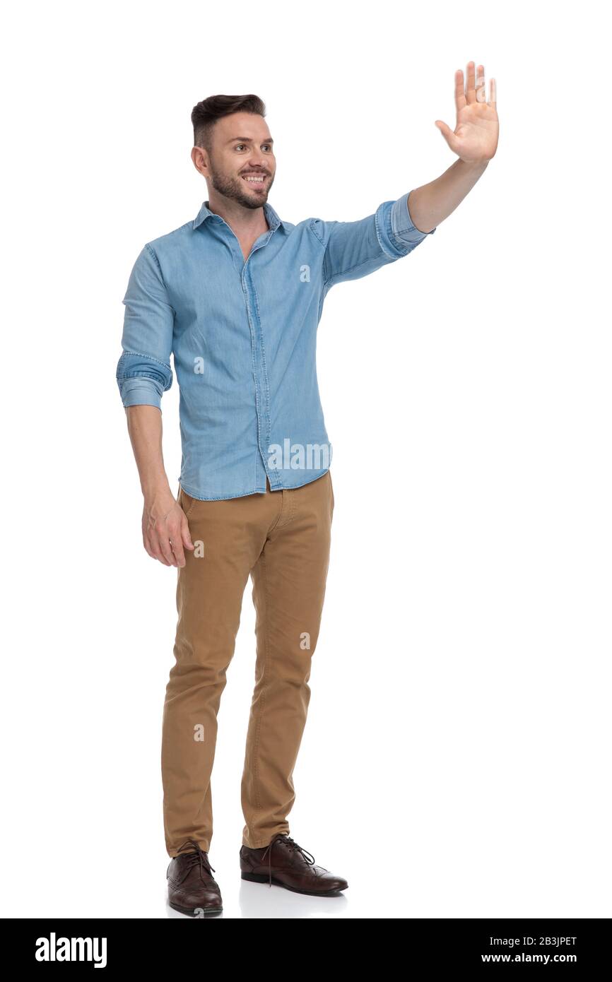 side view of a beautiful casual man with blue shirt standing and waving ...