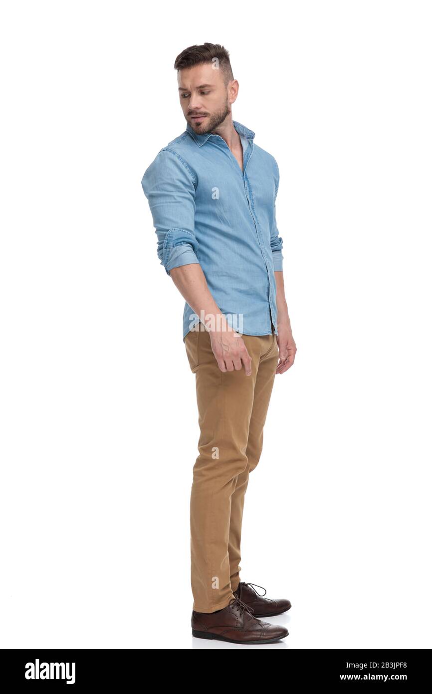 side view of a fit casual man with blue shirt standing and looking back ...