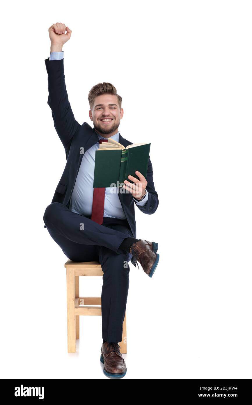 enthusiastic young businessman smiling, holding hand in the air and ...