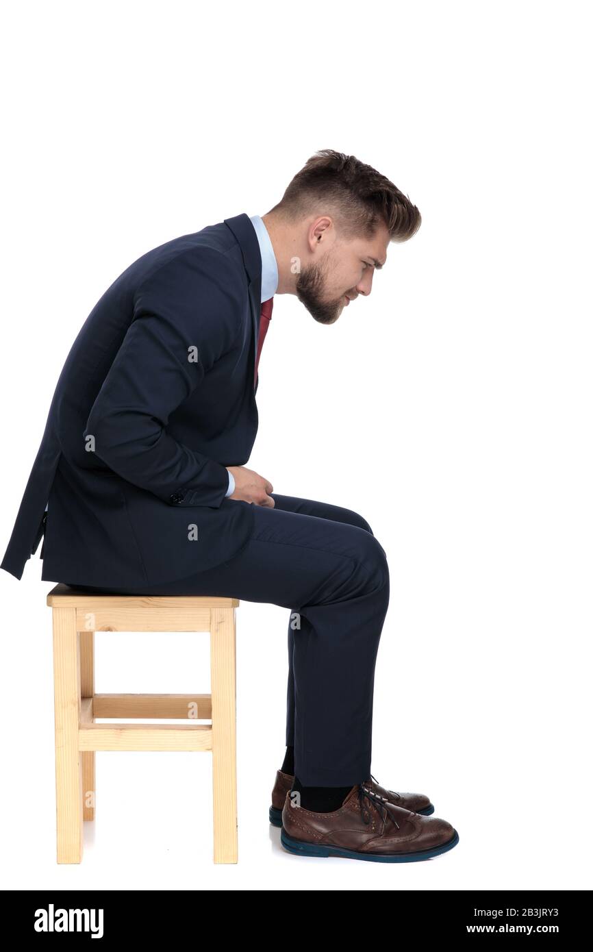 side view of young businessman looking down, trying to see something ...