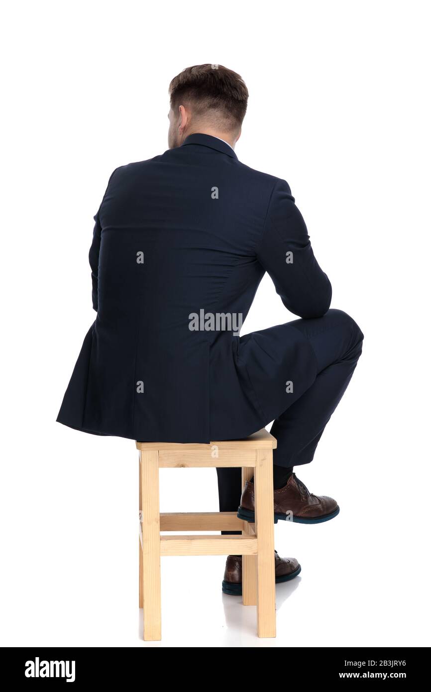 back view of young businessman looking to side and thinking, sitting ...