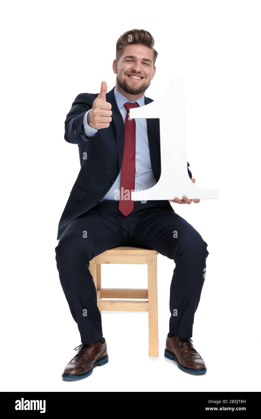happy young businessman smiling, making thumbs up sign and holding ...