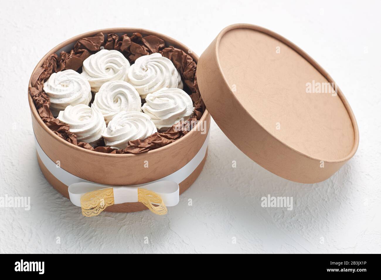 Delicious homemade zephyr packed in a brown round box on a white ...