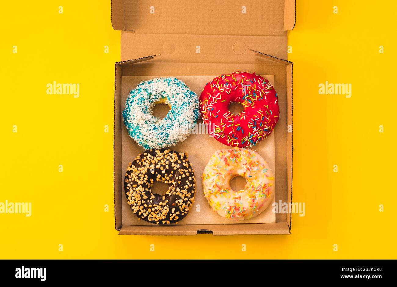 Delicious donuts lying on carton box on yellow background. Concept of ...